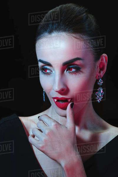 Attractive vampire touching her lips isolated on black - Royalty-free ...