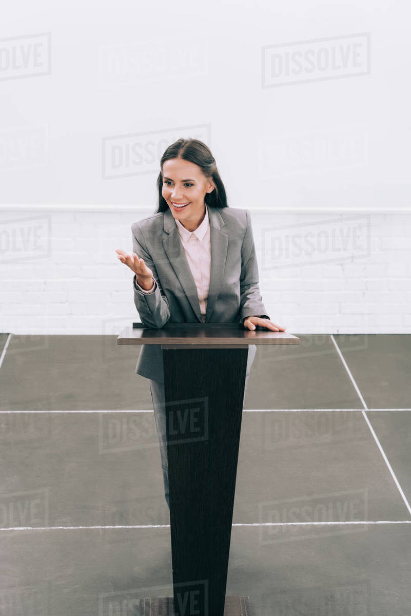 High angle view of attractive smiling lecturer gesturing at podium ...