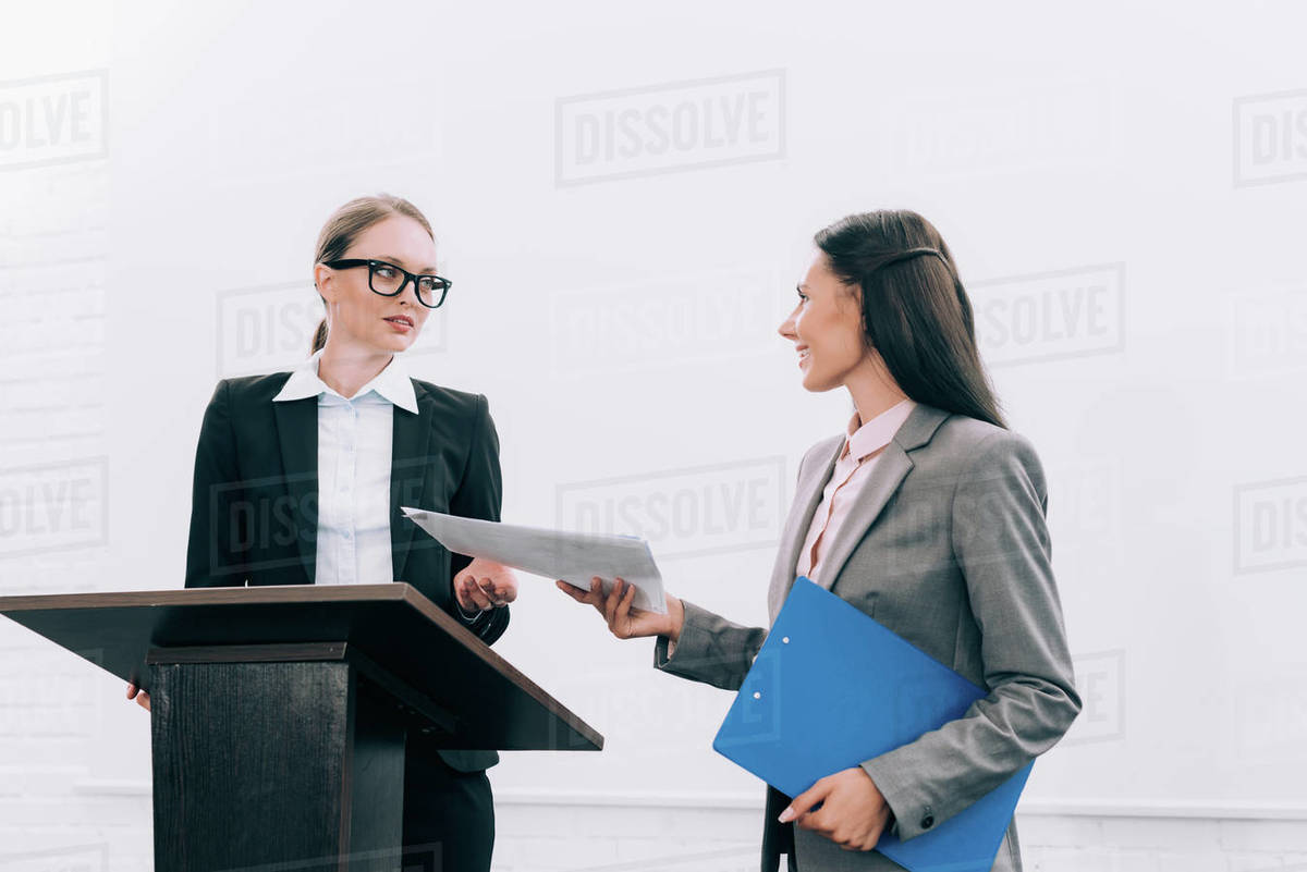 Beautiful assistant giving documents to attractive speaker during ...