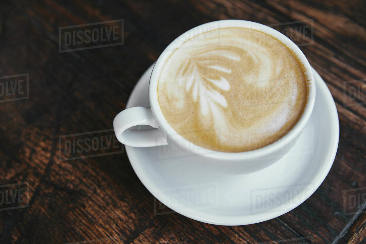 Cup of fresh coffee with latte art on rustic wooden table - Royalty ...