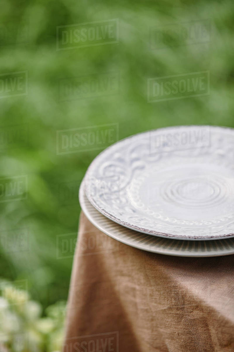Two plates on table in garden - Royalty-free Stock Photo | Dissolve