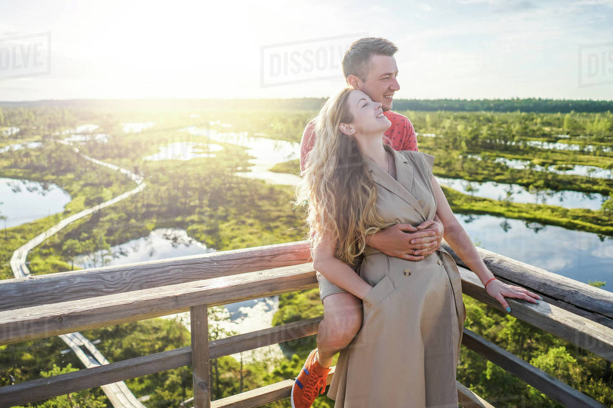 Portrait of affectionate couple in love hugging on wooden bridge ...
