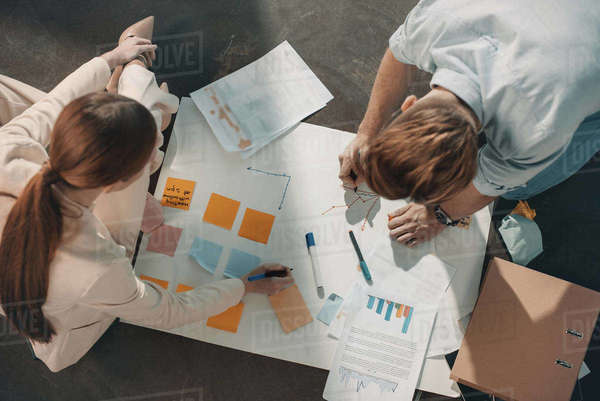 Overhead view of young business people sitting on floor and working ...