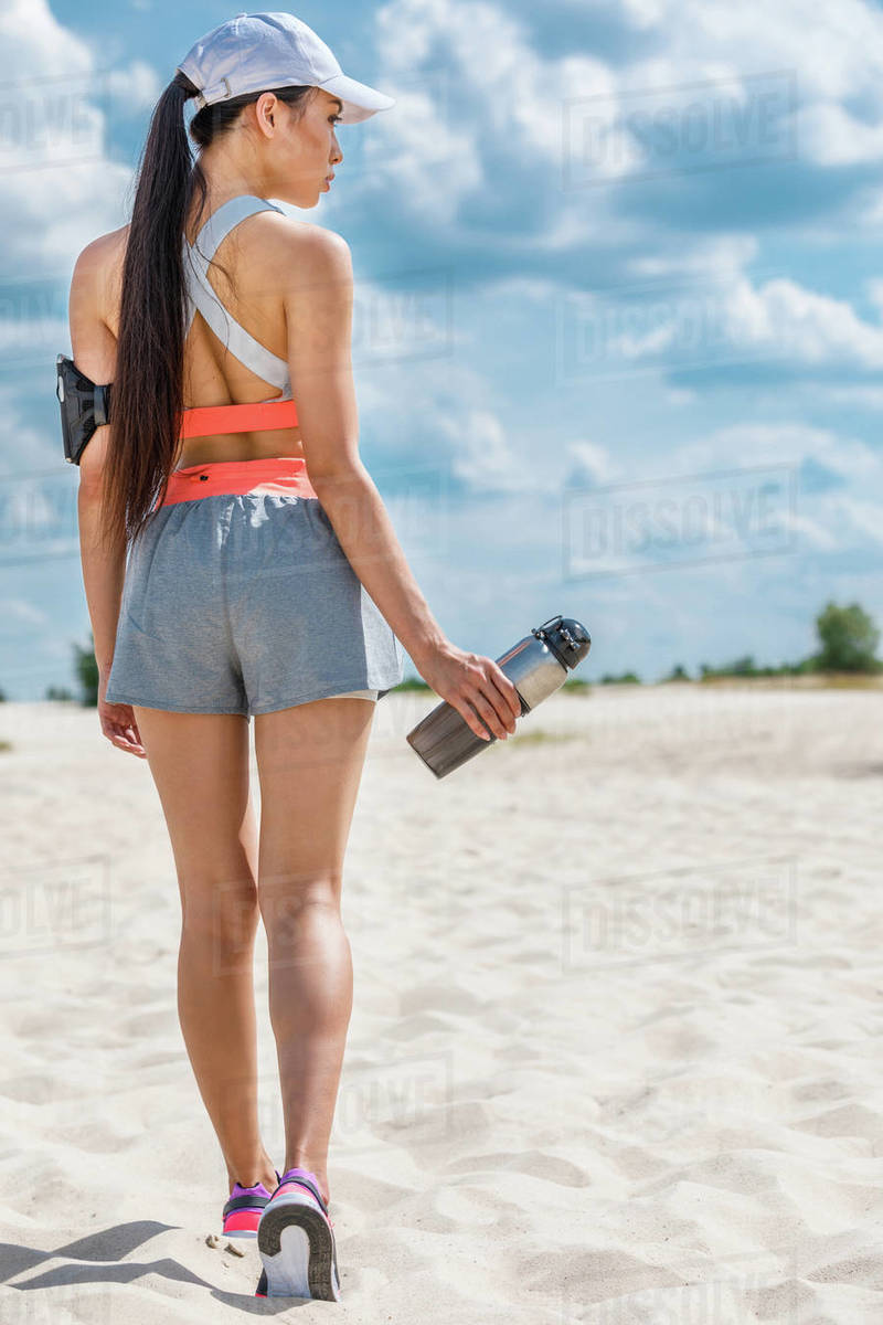 back view of asian sportswoman with sport bottle and sport armband for ...