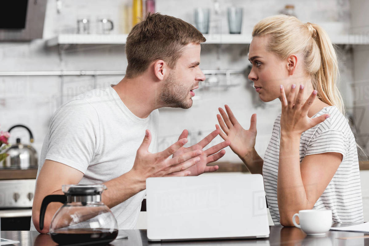 side view of emotional young couple arguing and looking at each other ...