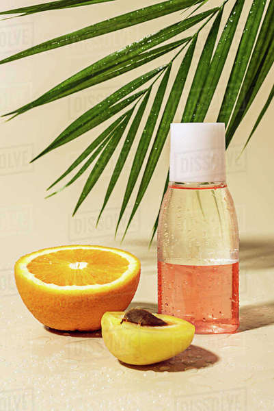 close up view of micellar water for skin care in bottle and orange half ...