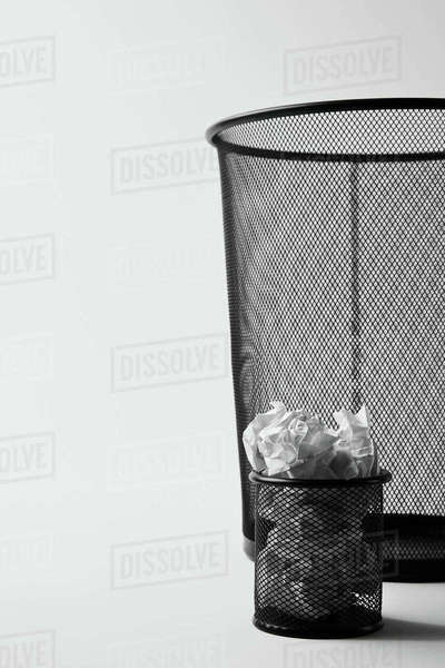 close-up shot of big and small office trash bins with crumpled papers ...
