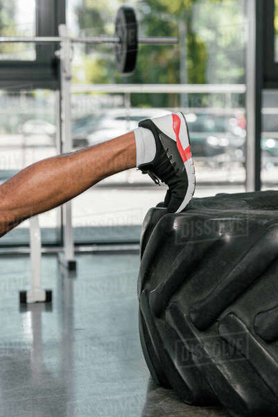 cropped shot of muscular male leg on tire in gym - Royalty-free Stock ...