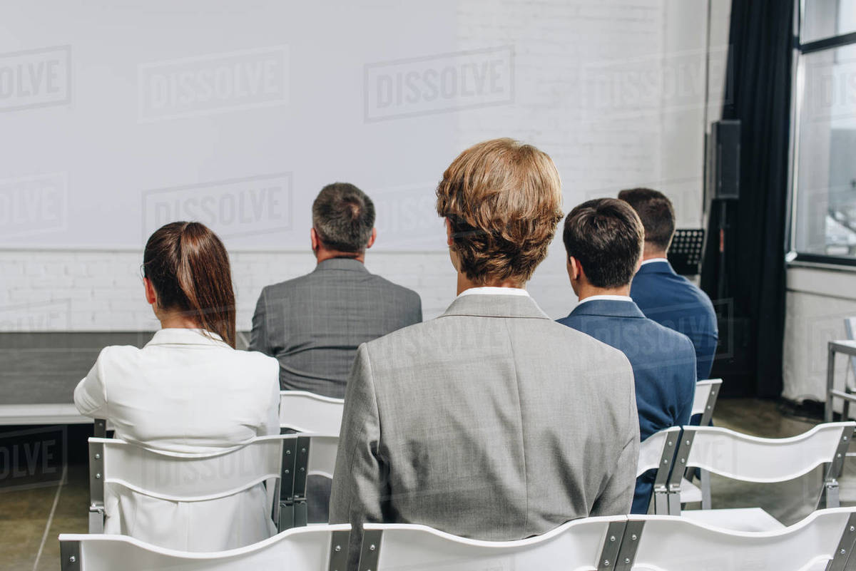 back view of businesspeople sitting on chairs at training in hub ...