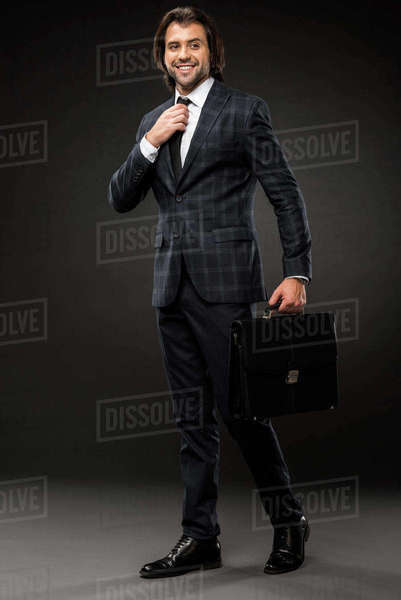 Full length view of handsome young businessman holding briefcase and ...