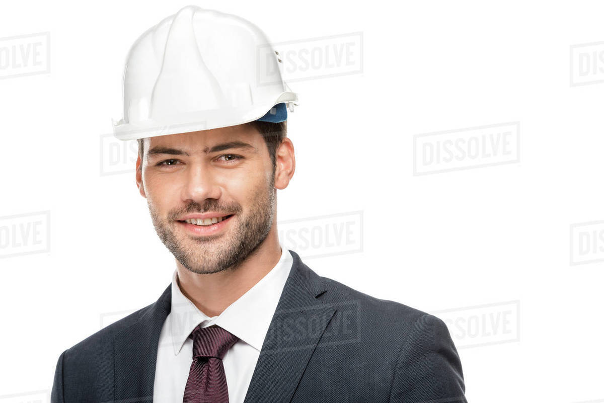 Portrait of young male architect in hard hat looking at camera isolated ...