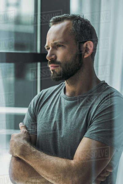 Serious bearded middle aged man standing with crossed arms and looking ...