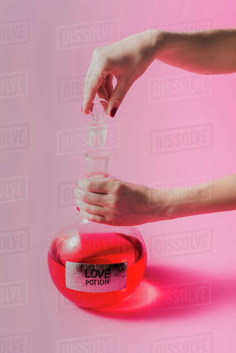 Cropped shot of woman opening flask with red colored love potion on ...