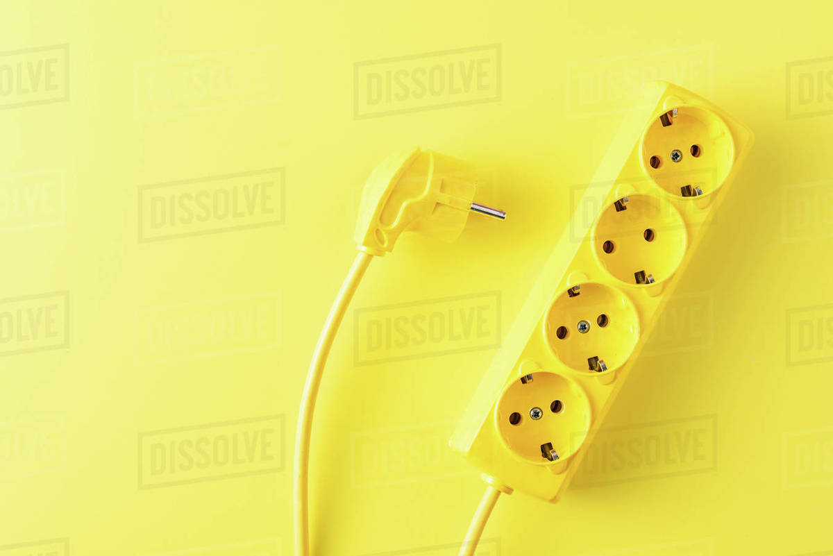 Top view of yellow socket outlet and plug on yellow background ...