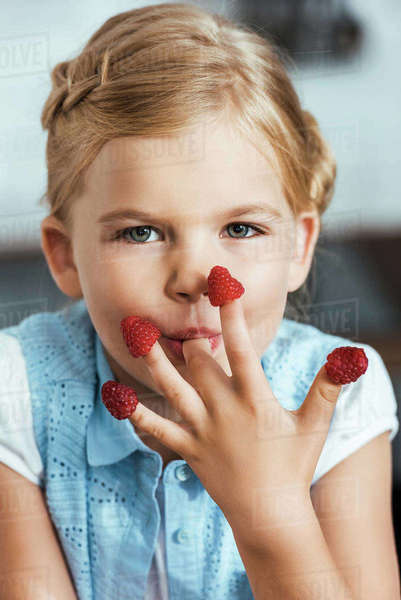 Adorable child eating raspberries and looking at camera - Stock Photo ...