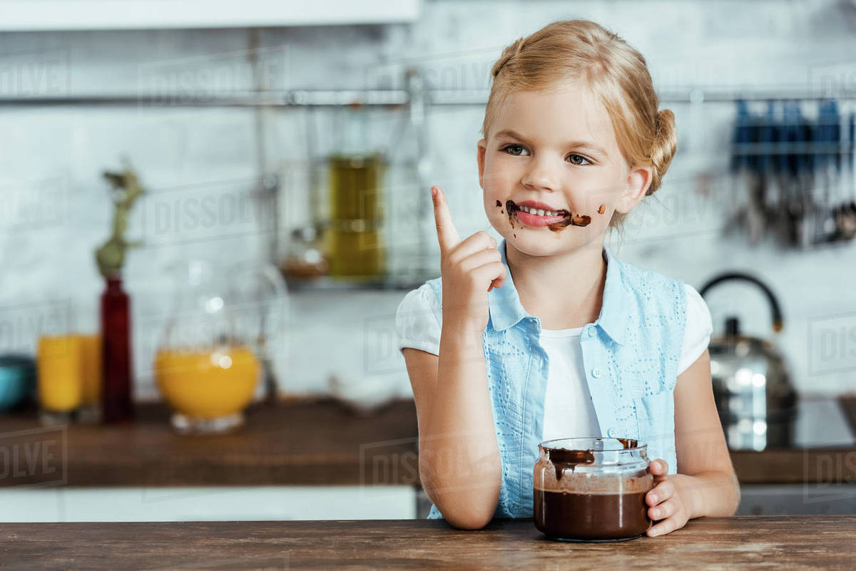 Cute happy child eating sweet chocolate spread - Stock Photo - Dissolve