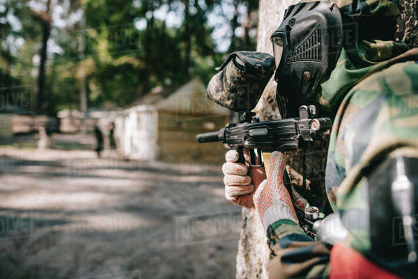 Selective focus of paintball player in goggle mask and camouflage ...