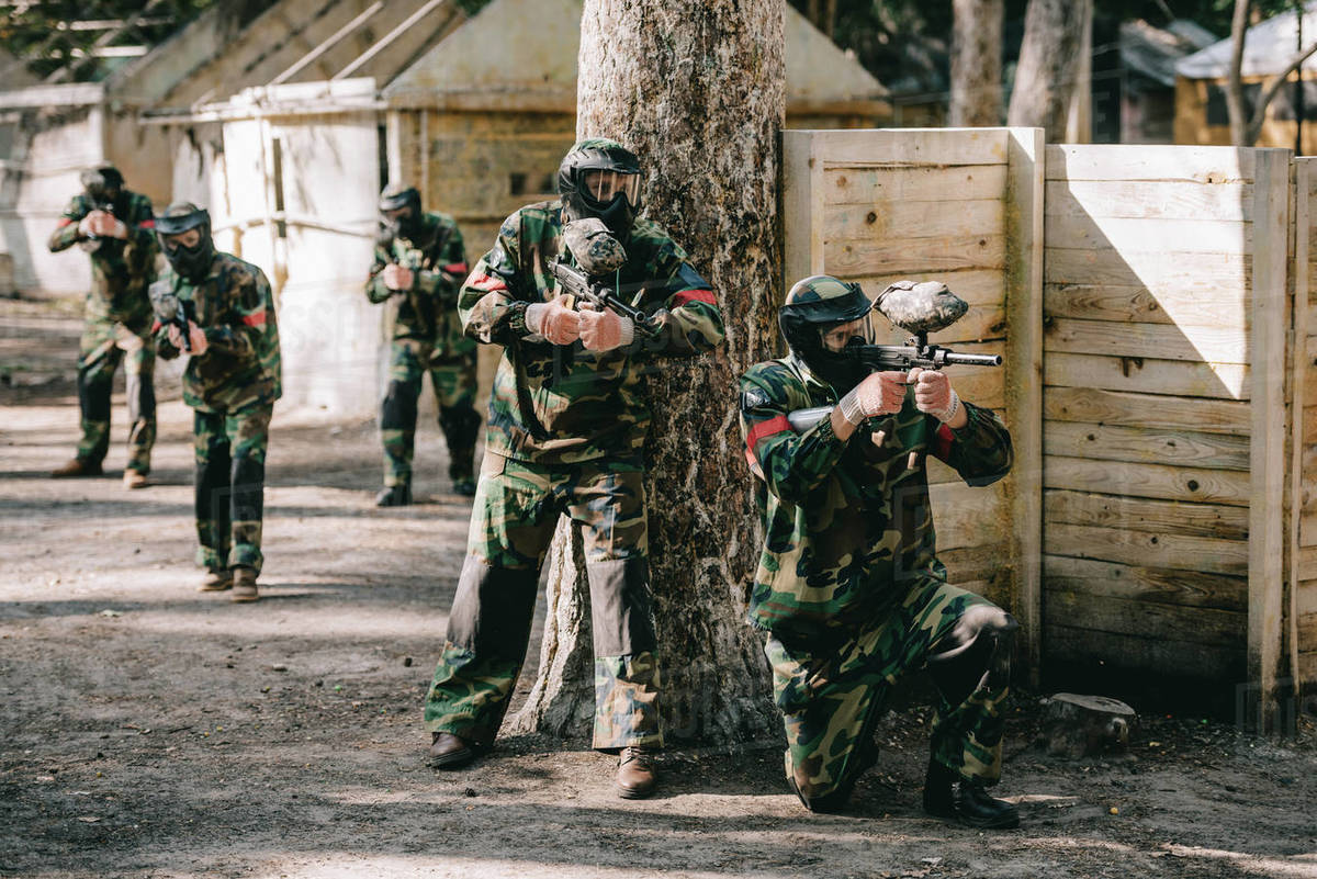 Paintball Players Wearing Camouflage And Goggle Masks Shooting By paintball-players-wearing-camouflage-and-goggle-masks-shooting-by