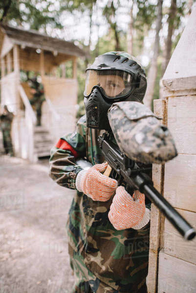 Focused male paintballer in goggle mask covered by paintball splash ...