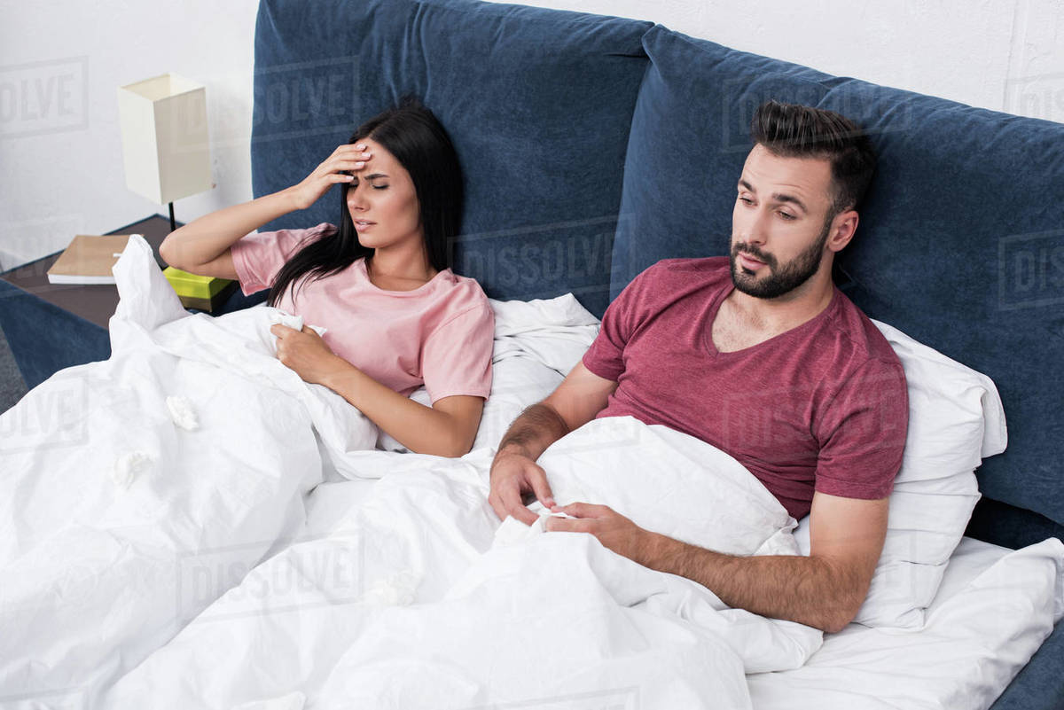 High angle view of young sick couple sitting in bed - Royalty-free ...