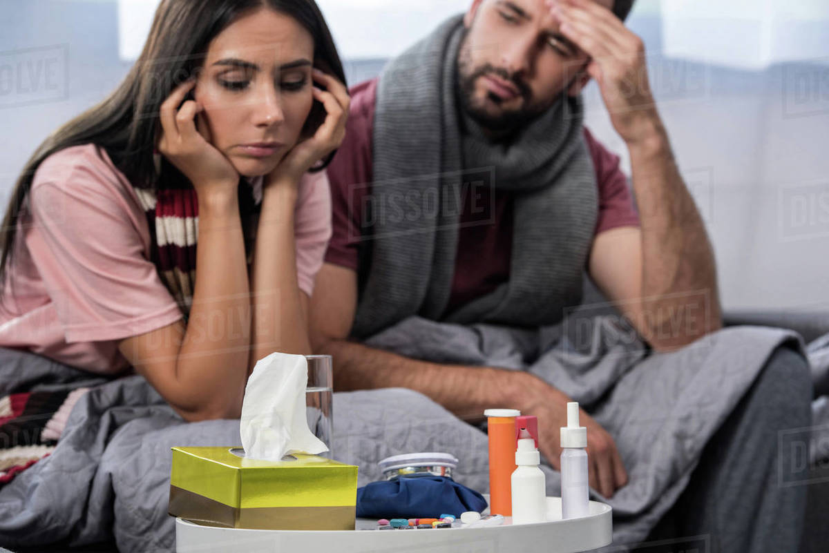 Sick couple with meds on table sitting together on couch - Royalty-free ...