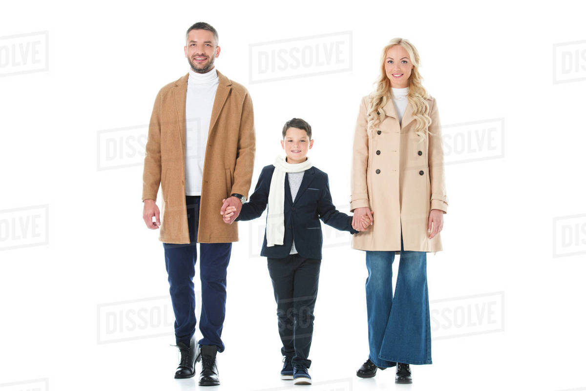 Parents in beige coats and son holding hands, isolated on white ...