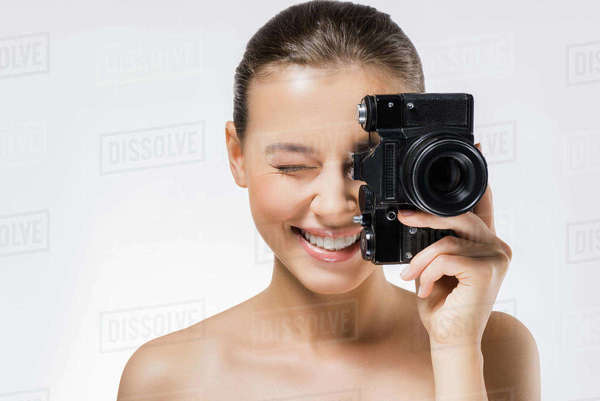 Young woman with closed eye hiding face behind black camera - Royalty ...