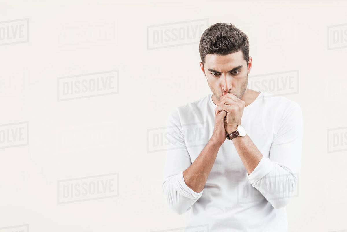 Focused young man thinking and looking down isolated on beige - Royalty ...