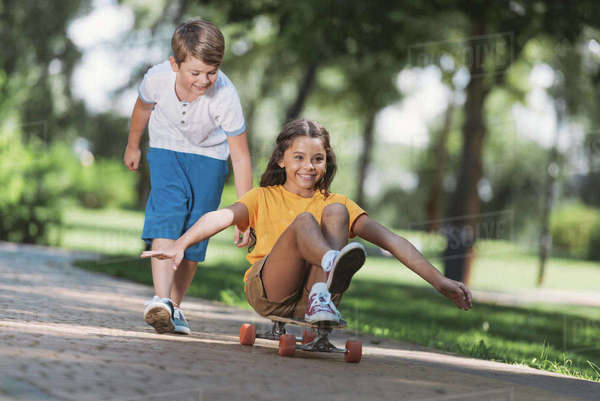 Adorable happy children having fun with longboard in park - Royalty ...