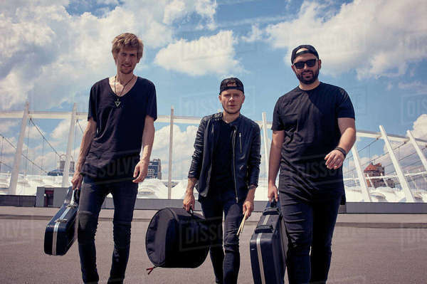 Young musicians with musical instruments in cases walking on street ...