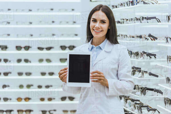 Attractive smiling optician showing digital tablet with blank screen in ...