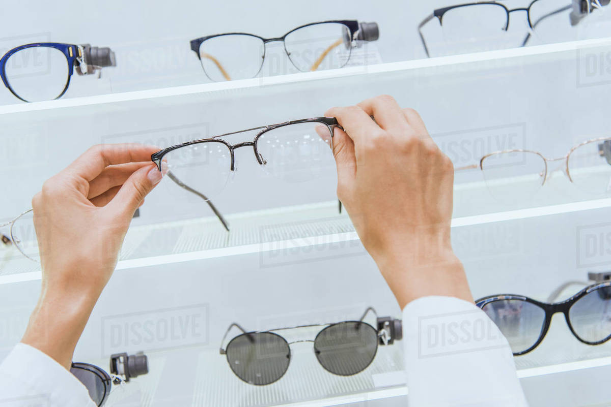 Cropped view of doctor taking eyeglasses from shelf in ophthalmic shop ...