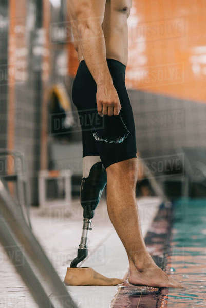 Cropped shot of swimmer with artificial leg standing on poolside at ...