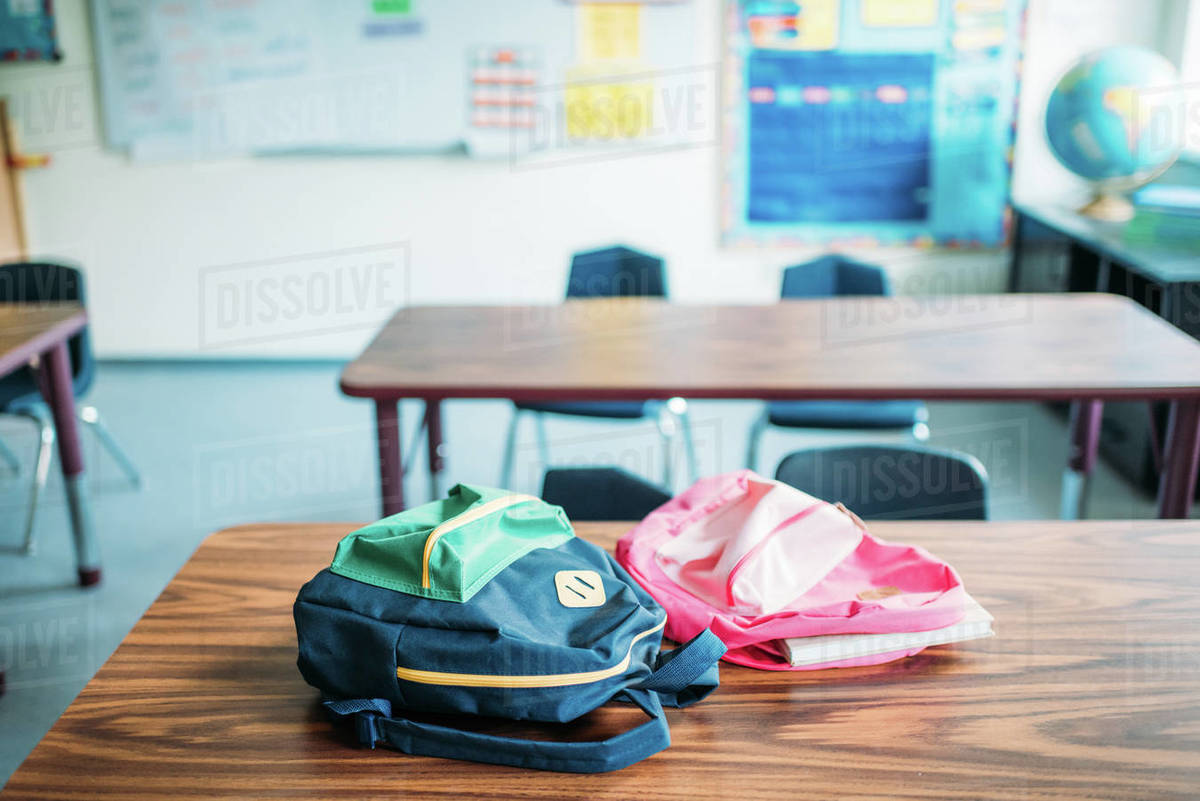 backpacks laying on desk in school classroom - Stock Photo - Dissolve