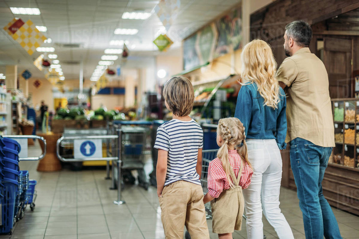 back view of young family with two children shopping together in ...