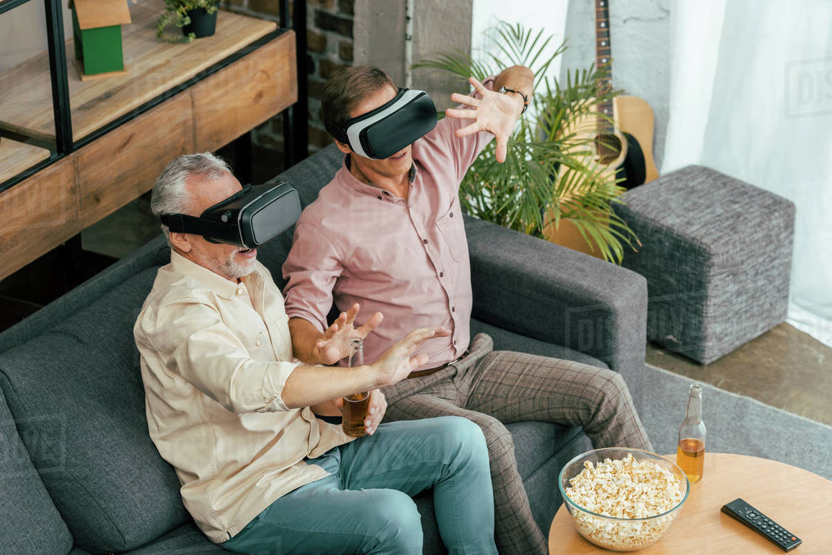 high angle view of mature men drinking beer and using virtual reality ...