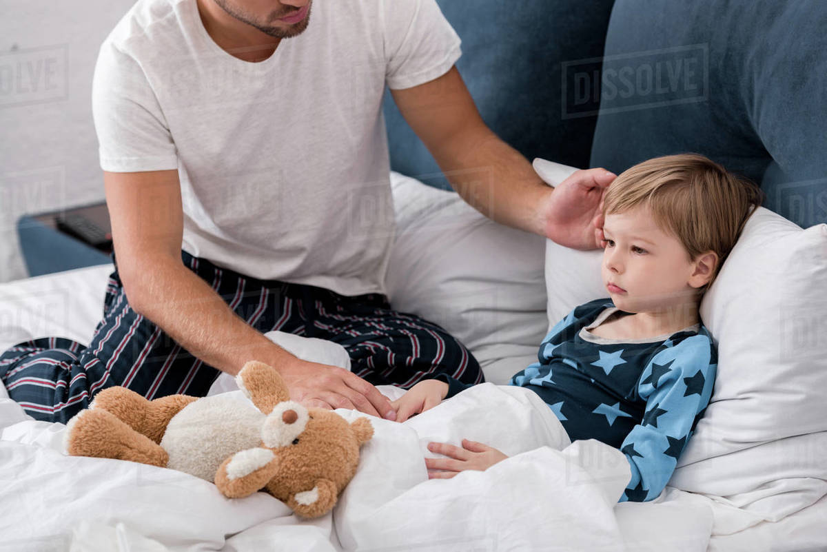 cropped shot of young father checking sons temperature with hand while ...