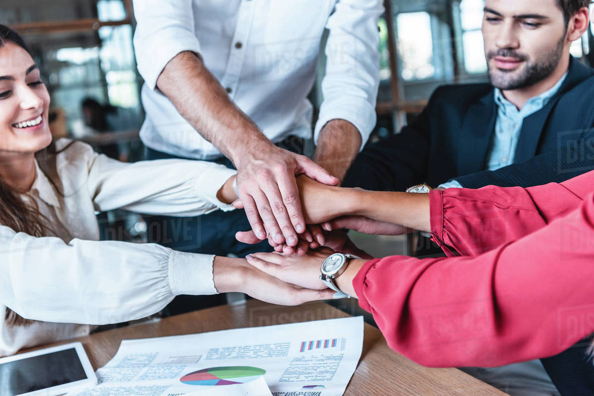 Cropped shot of business team holding hands at workplace in office ...