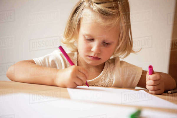 Serious adorable kid drawing with pink felt pen in kindergarten ...