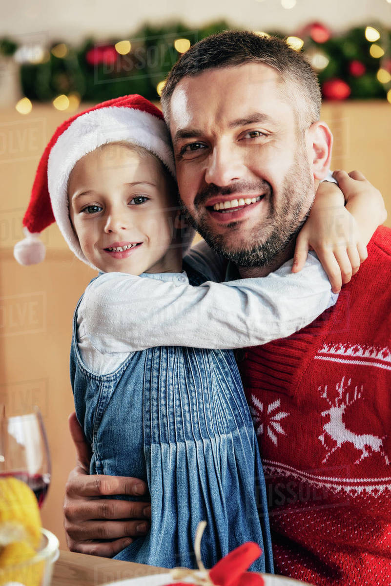 Portrait of happy little kid in christmas embracing father at table ...