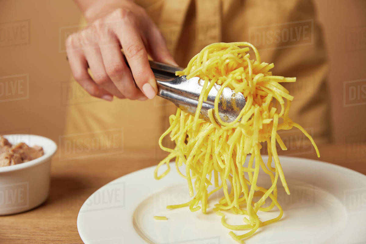 Cropped shot of woman putting spaghetti on plate with tongs - Royalty ...