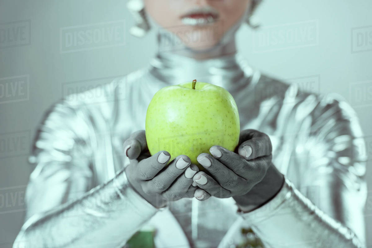Close-up partial view of cyborg holding green apple isolated on grey ...