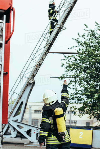 back view of female firefighter with fire extinguisher on back ...