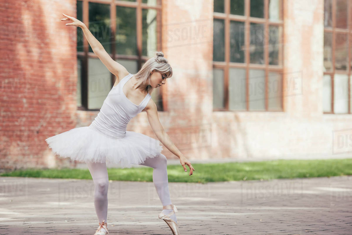 Attractive young ballerina in tutu skirt dancing on urban street ...