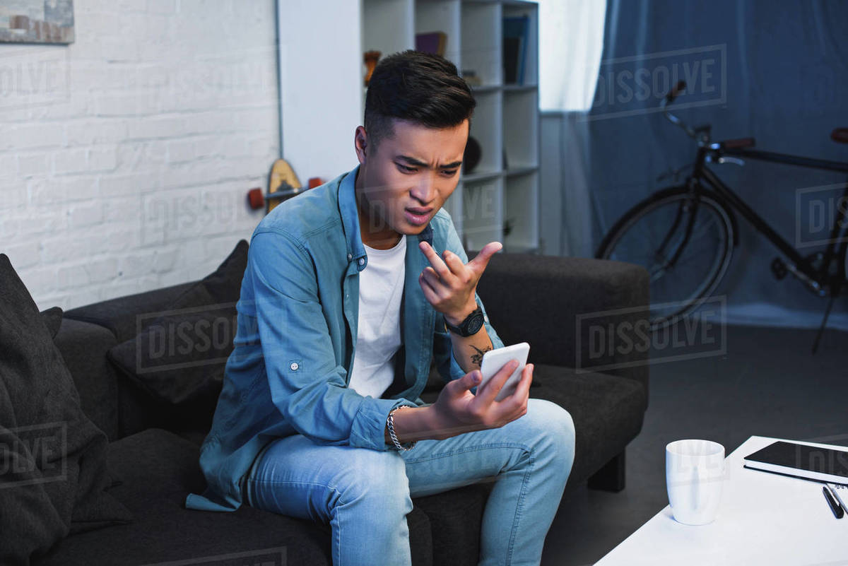 Young Asian man using smartphone and giving middle finger - Stock Photo ...
