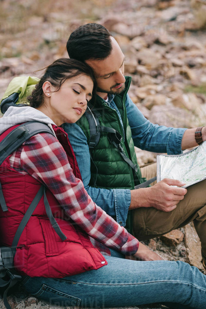 Side view of hikers with backpacks and map resting on rocks - Royalty ...