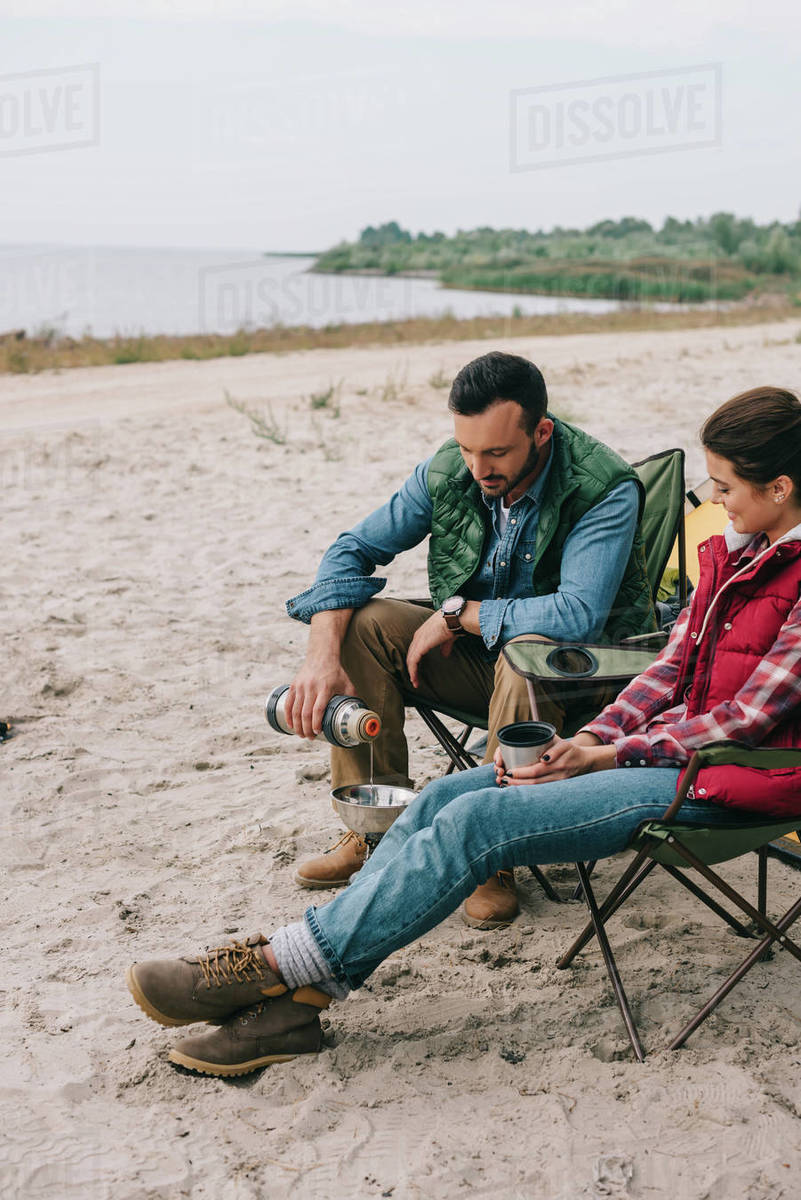Side view of couple having camping on sandy beach - Stock Photo - Dissolve