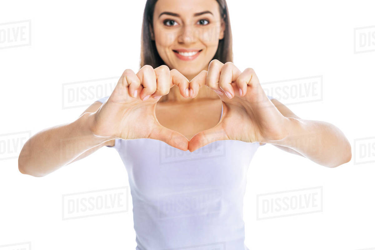 Portrait of smiling woman showing heart sign isolated on white ...