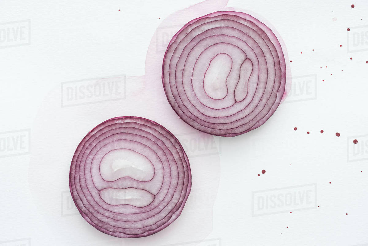 Top view of two slices of red onion on white surface with pink ...