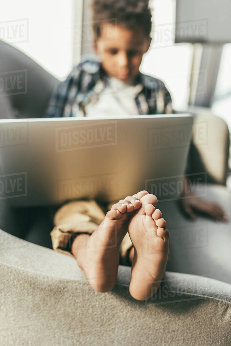 Close-up shot of bare little boy with laptop in armchair - Royalty-free ...